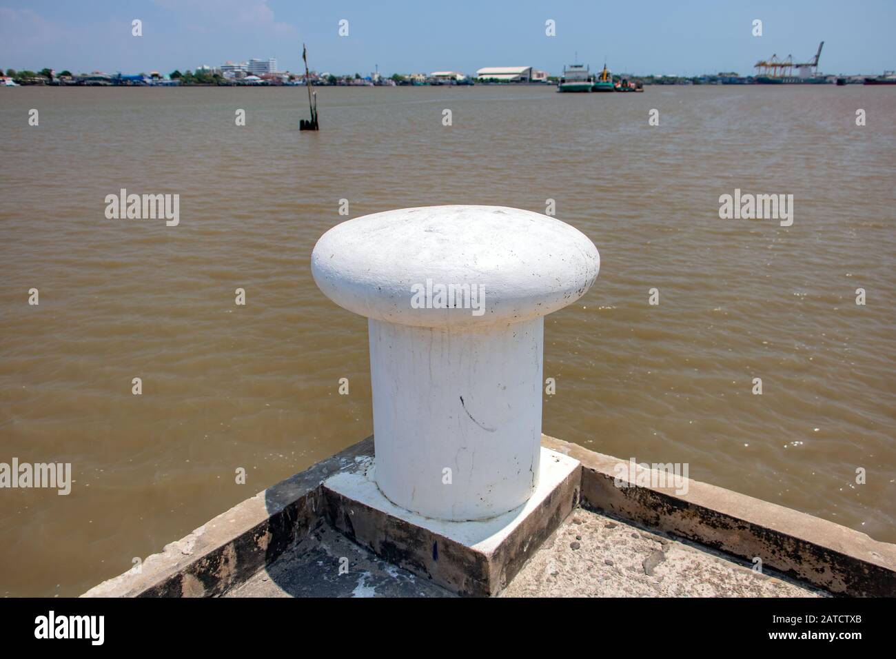 A shore with a white sea bollard on pier. The Large mooring bollard in ...