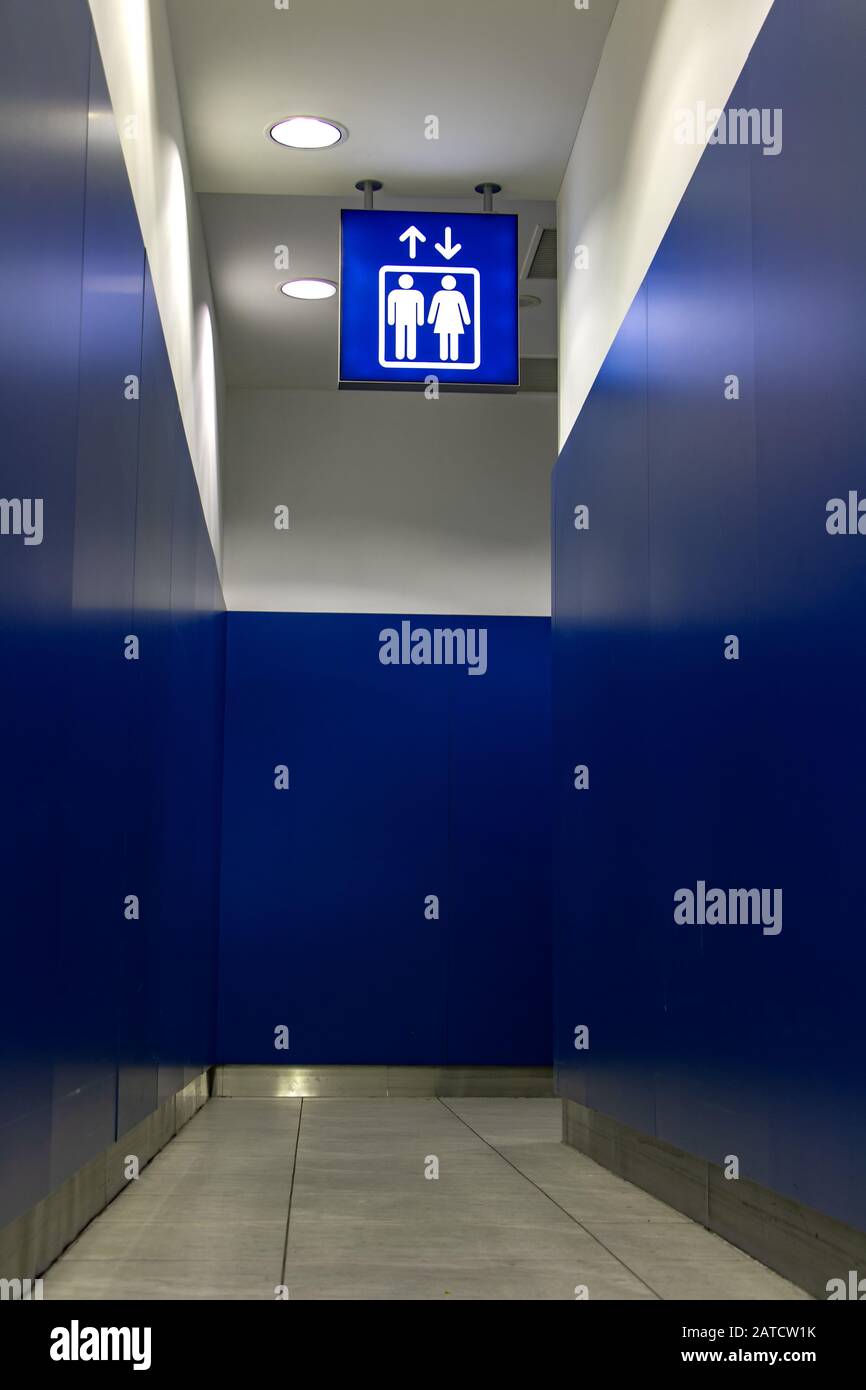 An illuminated sign with the icon of a lift hang on ceiling of the blue ...