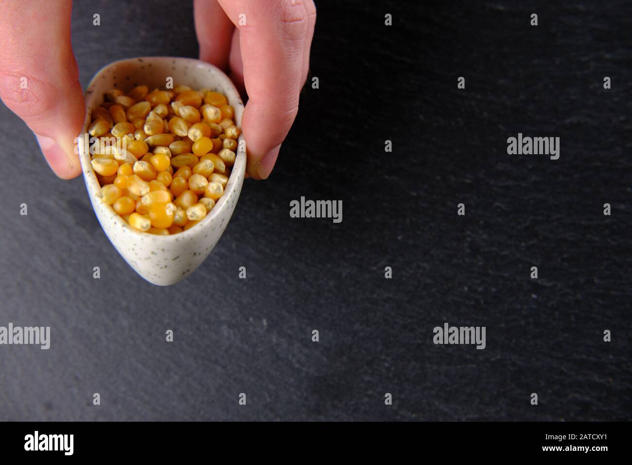 white plate full of corn popping kernels for popcorn at the black ...
