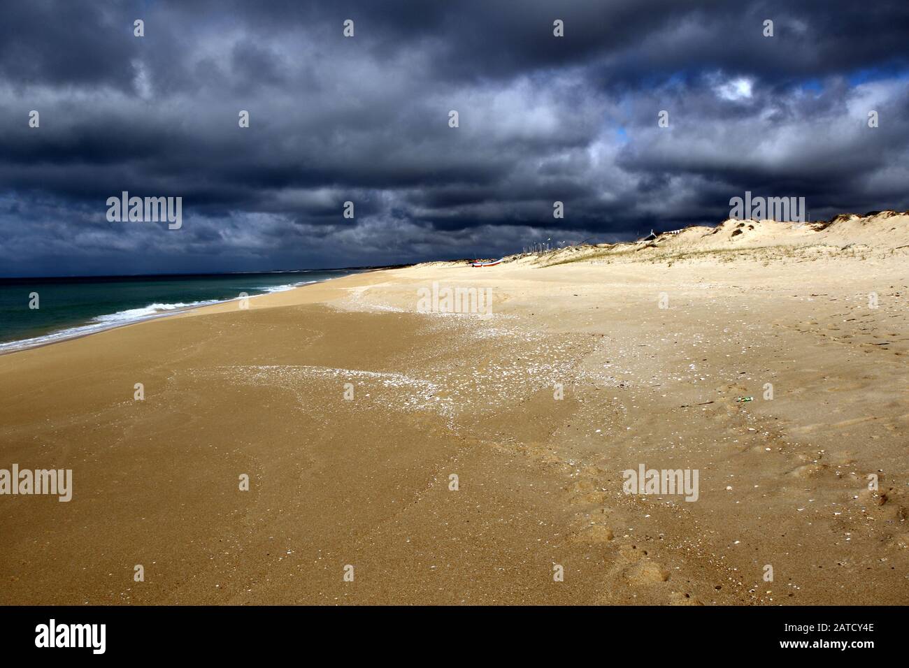 Sandy beach and navy blue ocean beneath the dark cloudy sky Stock Photo ...