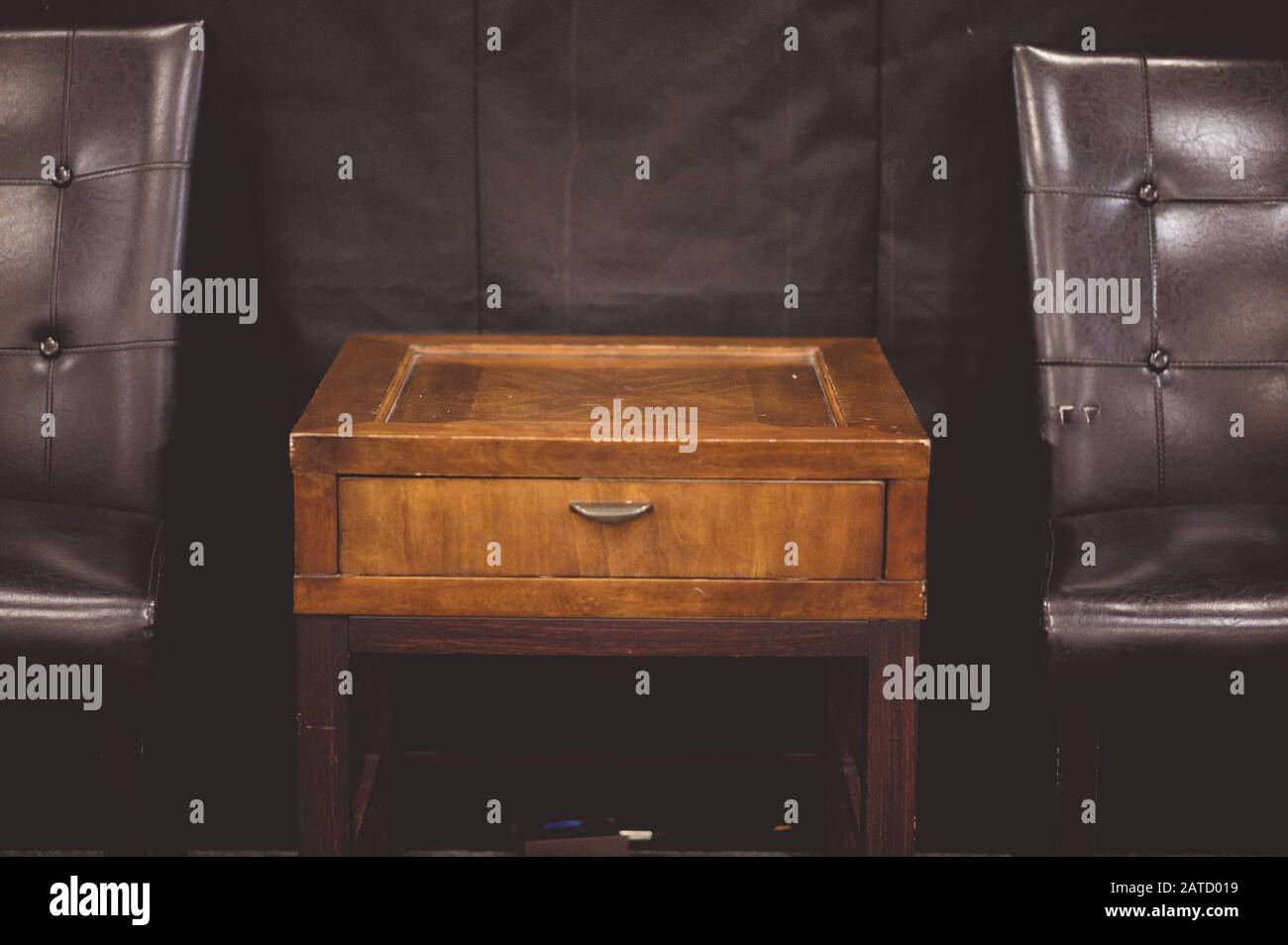 Small wooden table between two leather chairs Stock Photo - Alamy