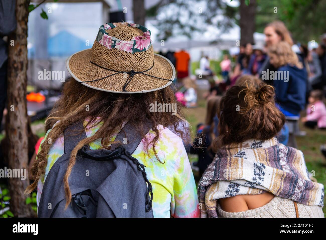 Rear view of female wearing wicker sun hat by friend against audience ...