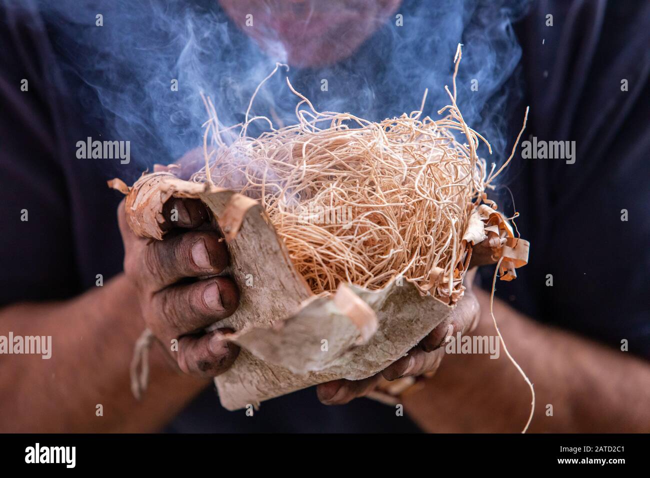 Closeup of man hand holding straw used as fire starter with smoke ...
