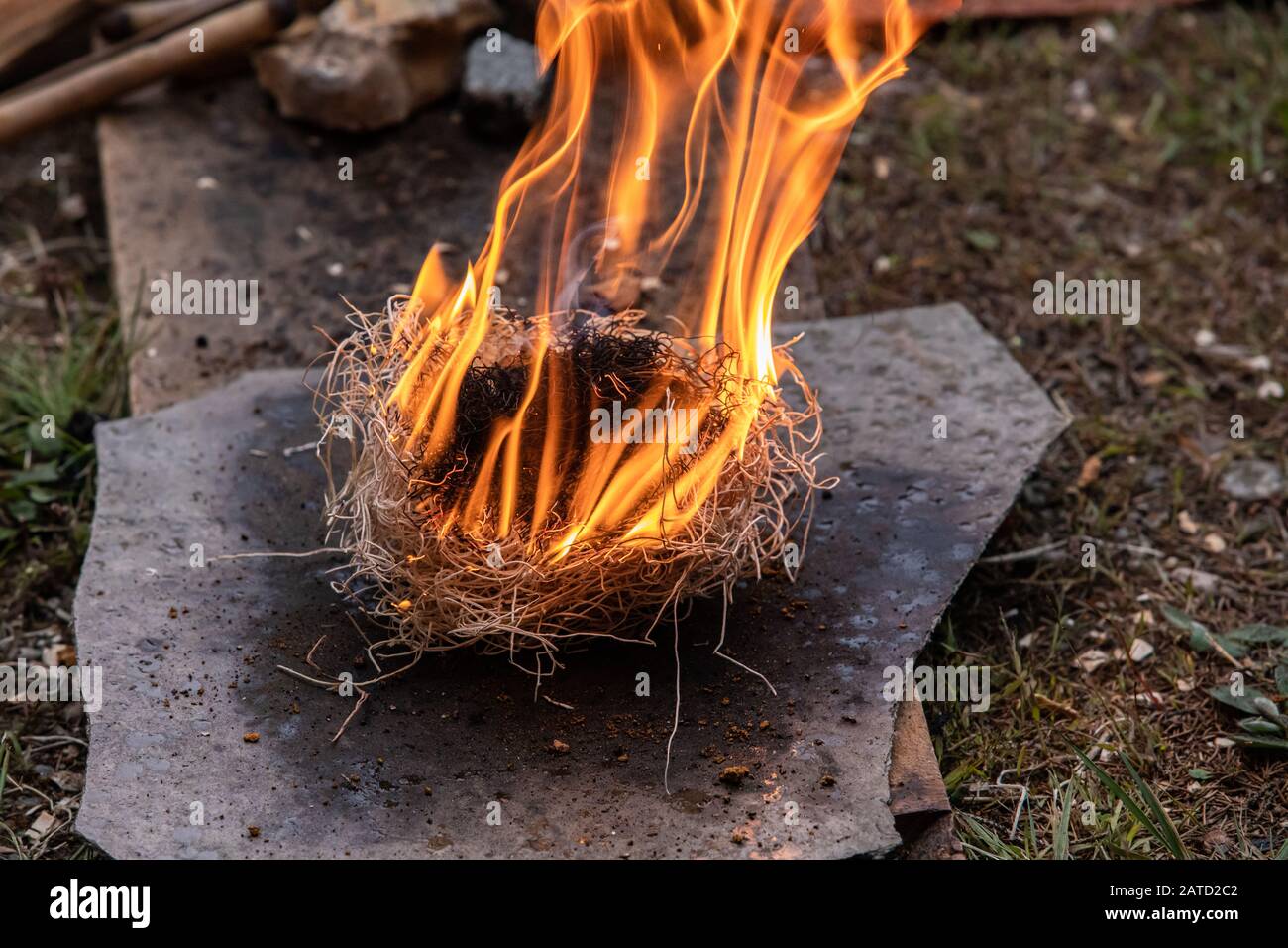 Flame burning using straw as fire starter on grey slate during ...