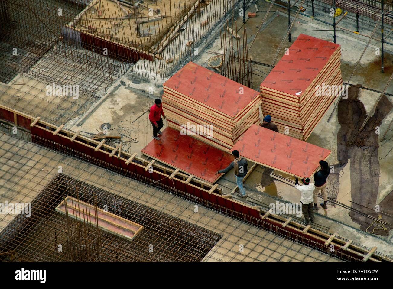 Construction workers in India moving wooden boards on near a work site ...