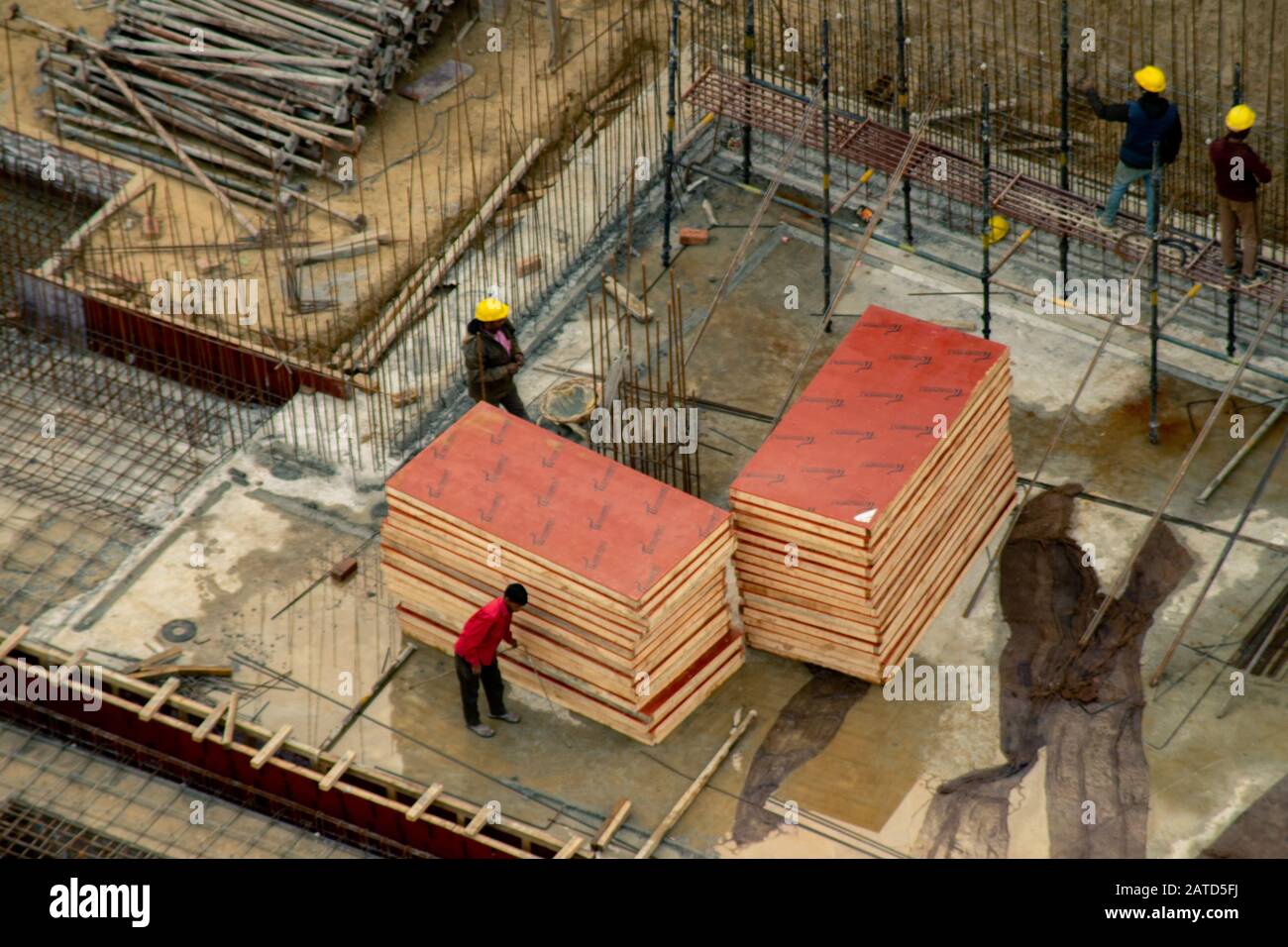 Construction workers in India moving wooden boards on near a work site ...
