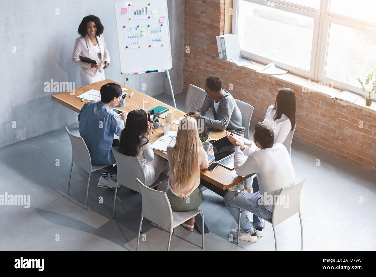 African young woman making marketing report in front of colleagues ...