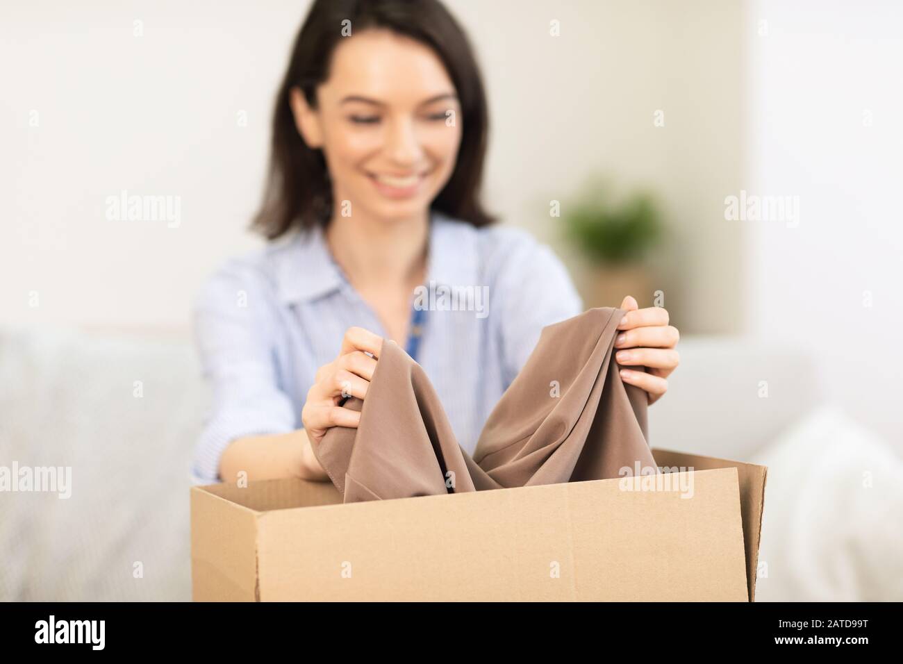 Happy young girl packing clothes for delivery Stock Photo - Alamy