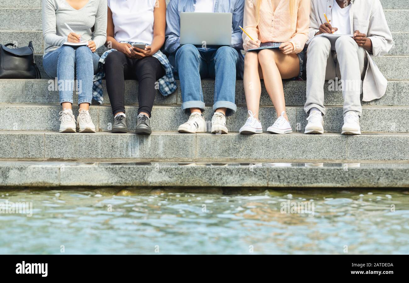 Group of students studying next to river, cropped Stock Photo - Alamy