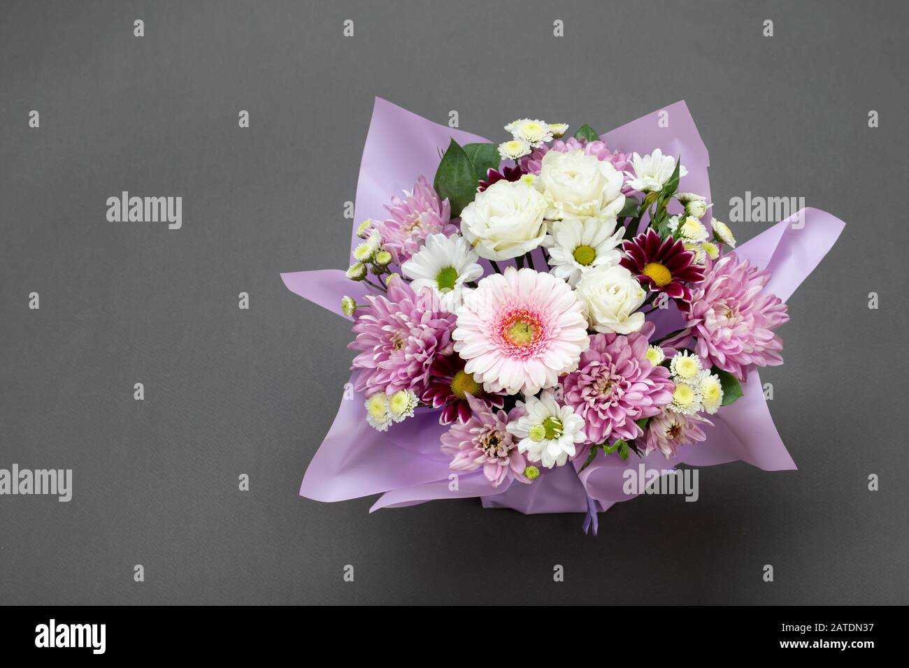 holiday bouquet of different flowers in a paper wrapper. on a neutral ...