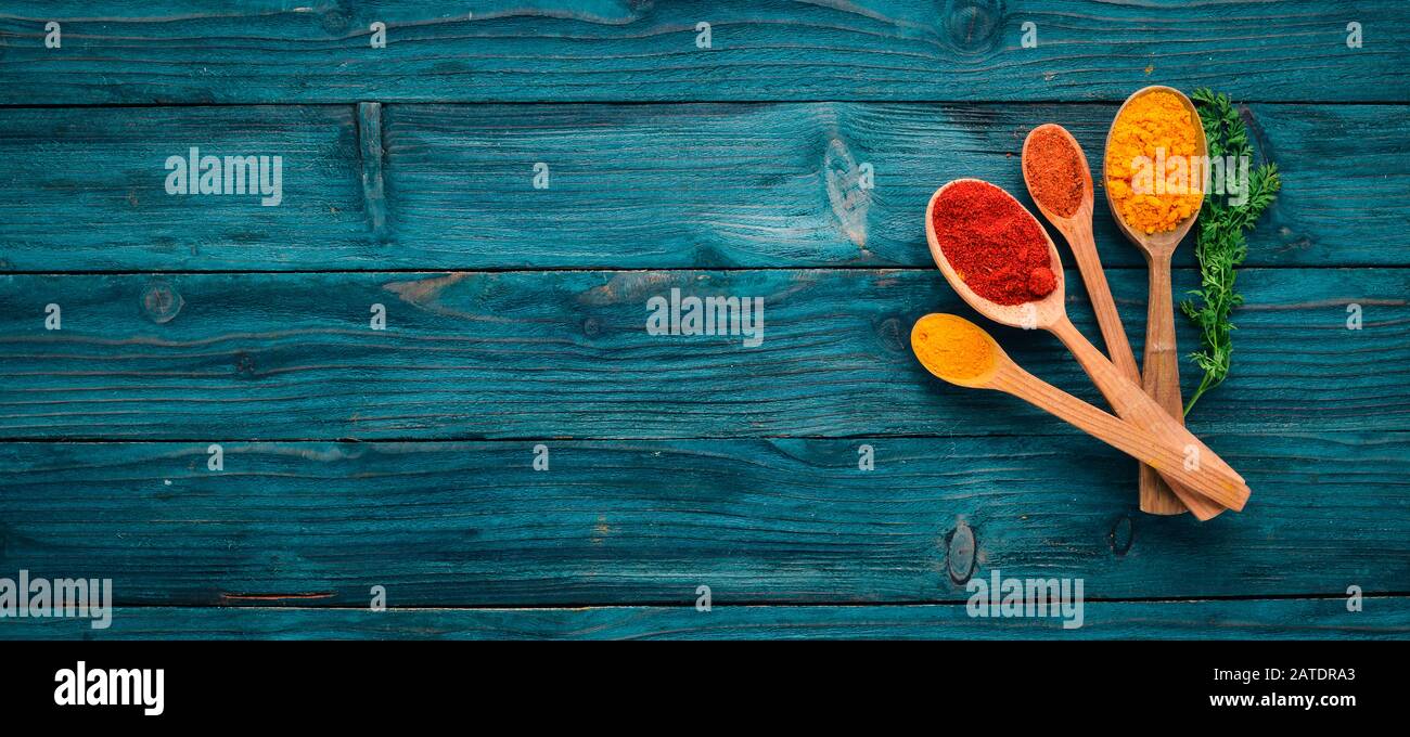 Spices and herbs on a blue wooden table. Basil, pepper, saffron, spices ...
