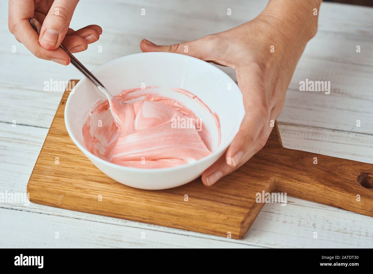 Woman whisking red cream for decorating cookies in bowl on kitchen ...