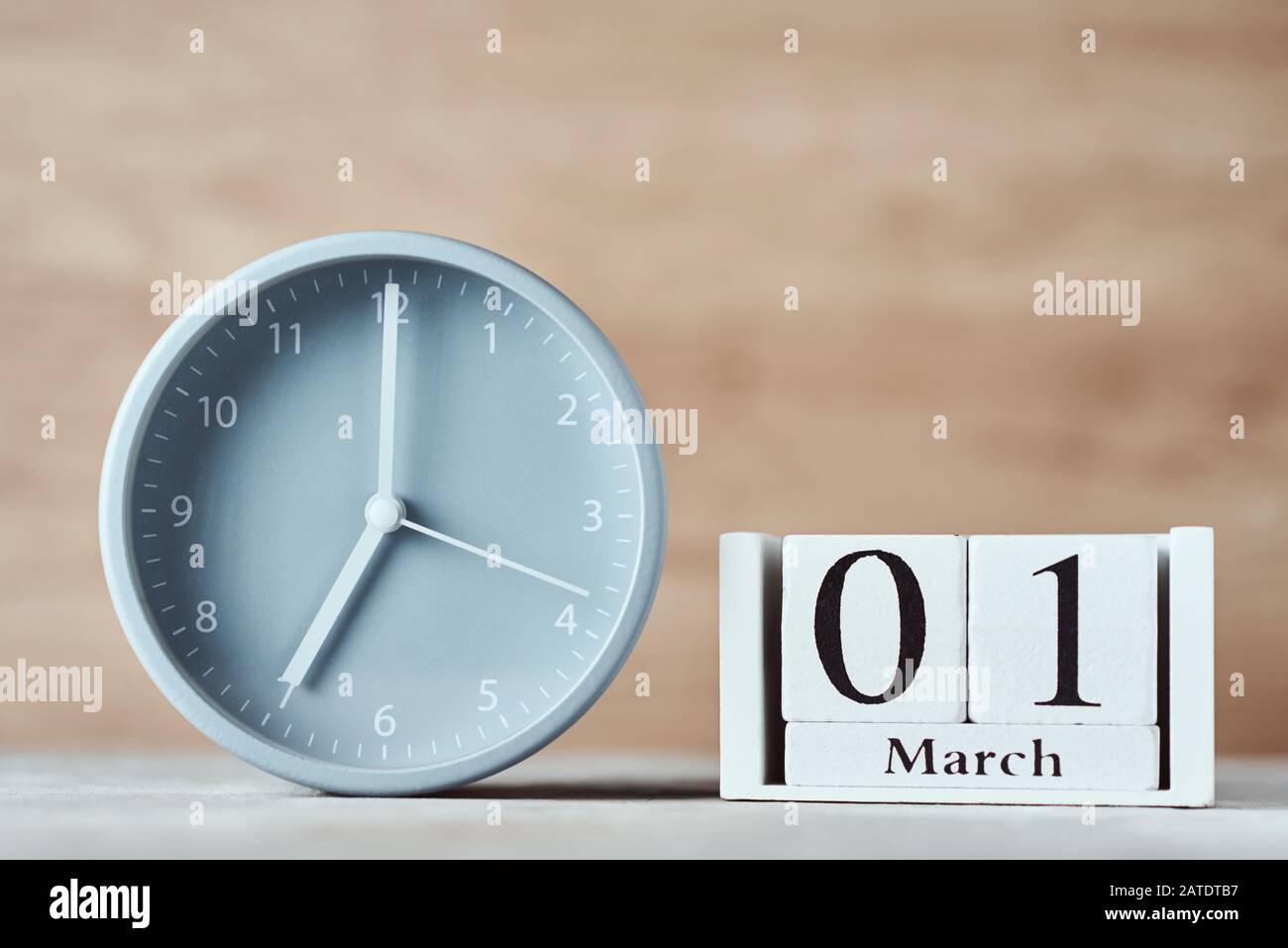 Alarm clock and wooden block calendar with date 1st march on table ...