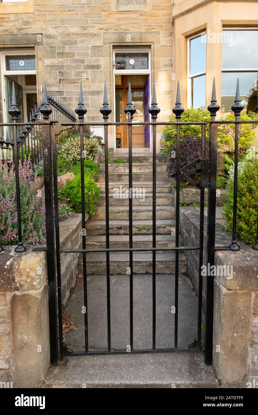 Wrought iron black gate with spikes, with steps and path to open front ...