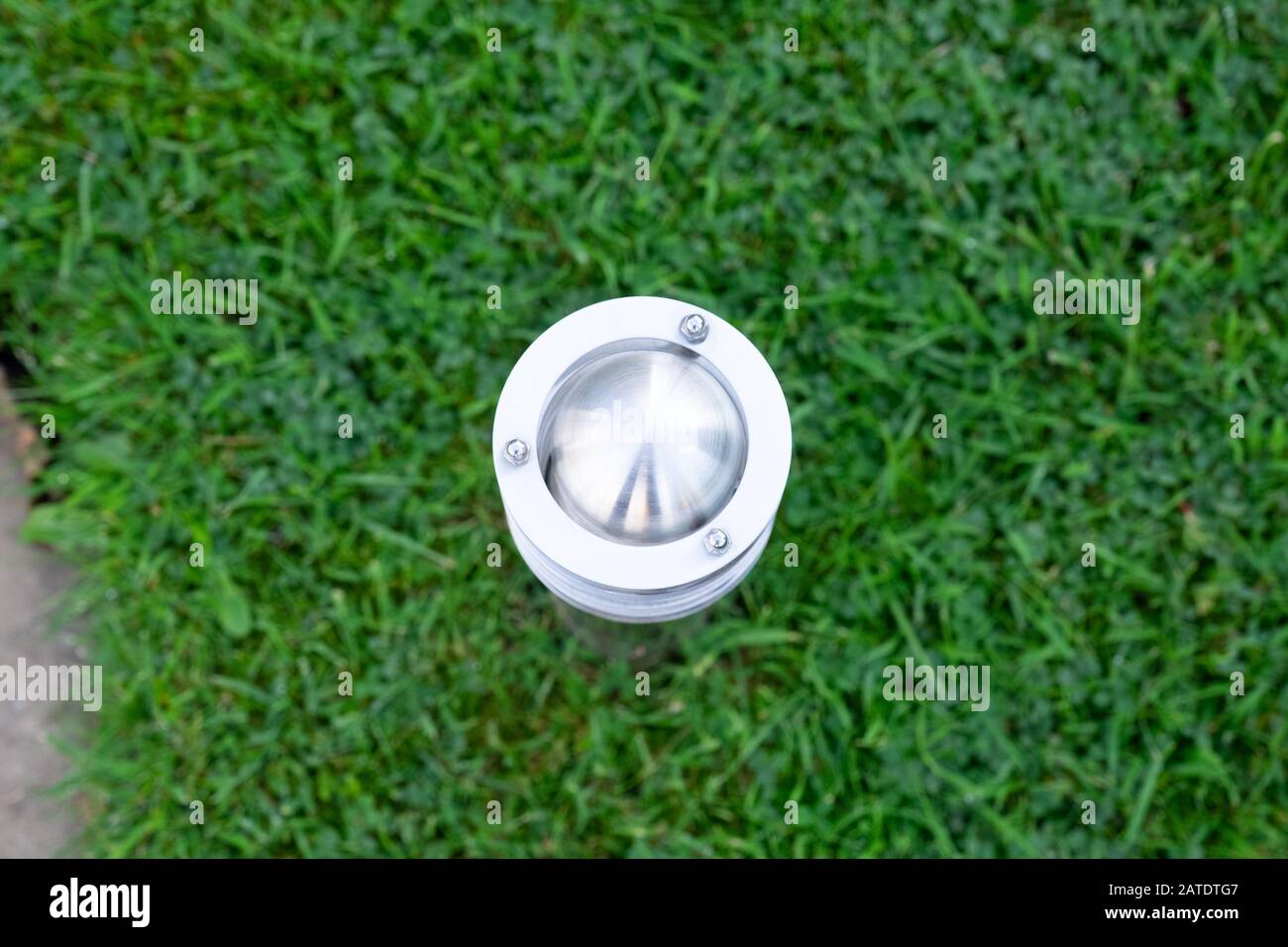 Top view of a small modern metal silver, outdoor garden light on a lawn ...