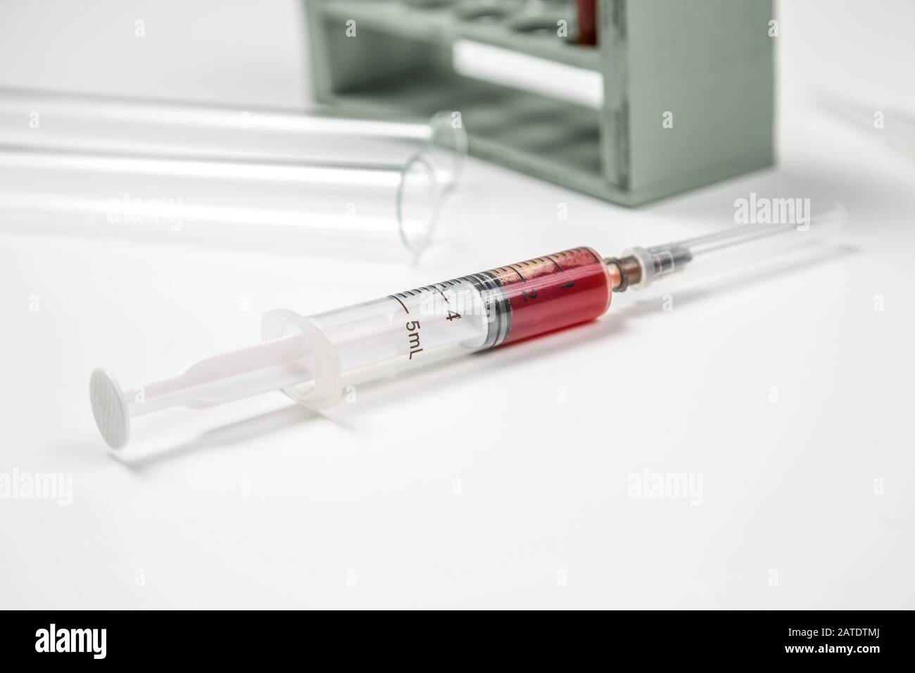 a sterile syringe with a blood sample on a white medical table ...