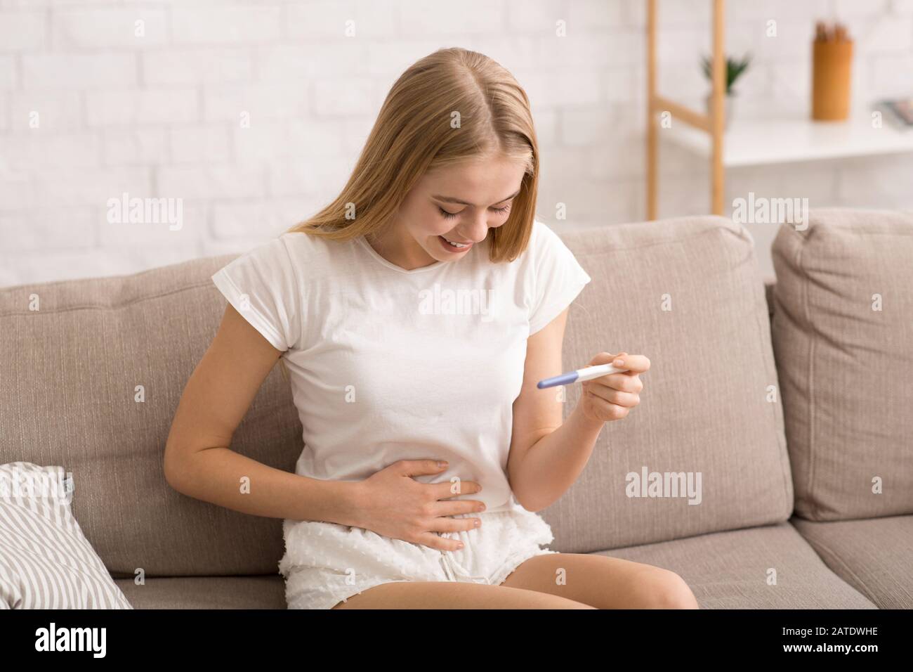 Excited girl in pajama holding positive pregnancy test Stock Photo - Alamy