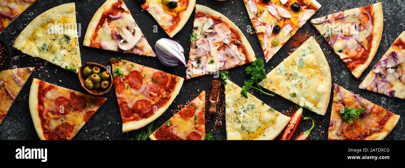 Assortment of pizza sliced on black stone background. Top view. free ...