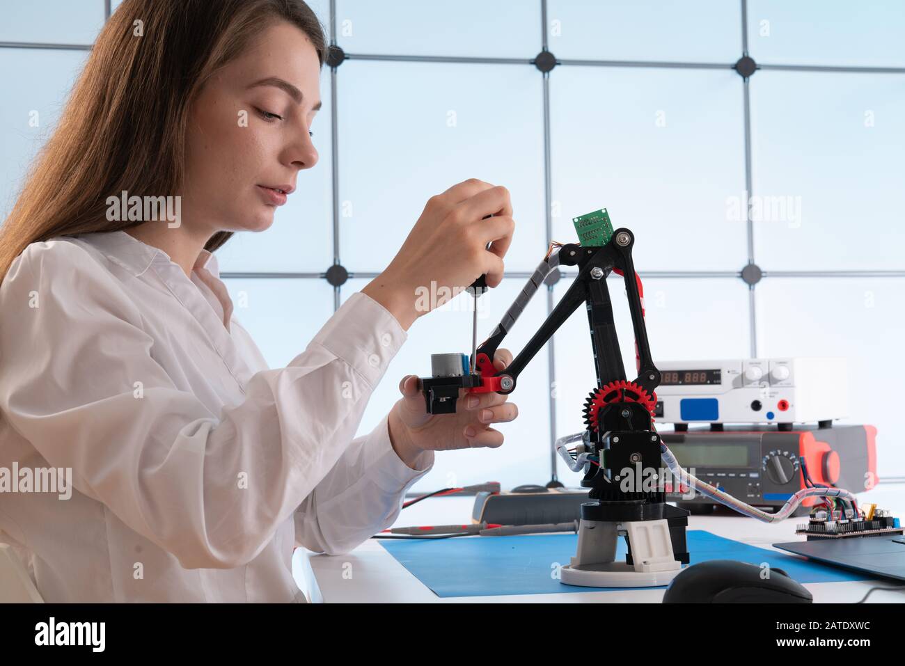 A young woman writes an algorithm for the robot arm. Science Research ...