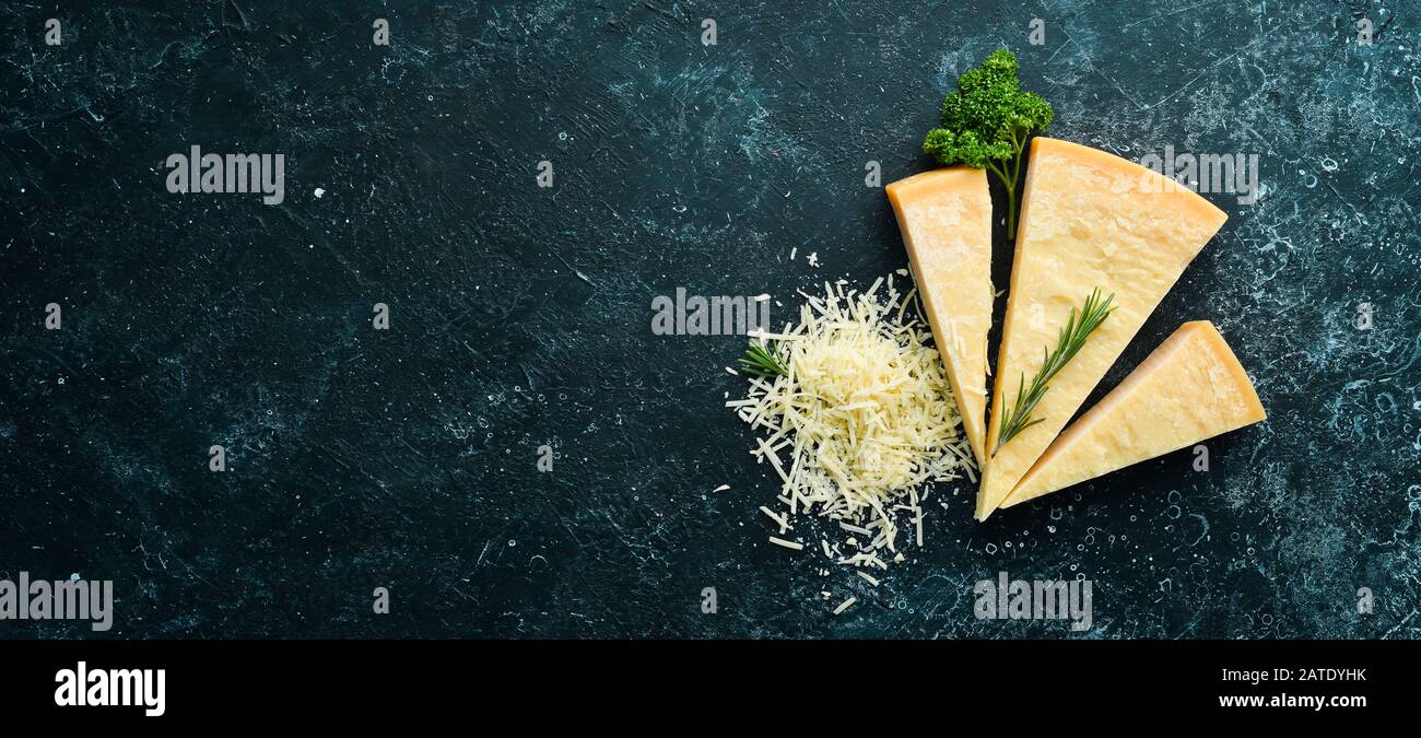 Parmesan. Pieces of Parmesan cheese on black stone background. Top view ...