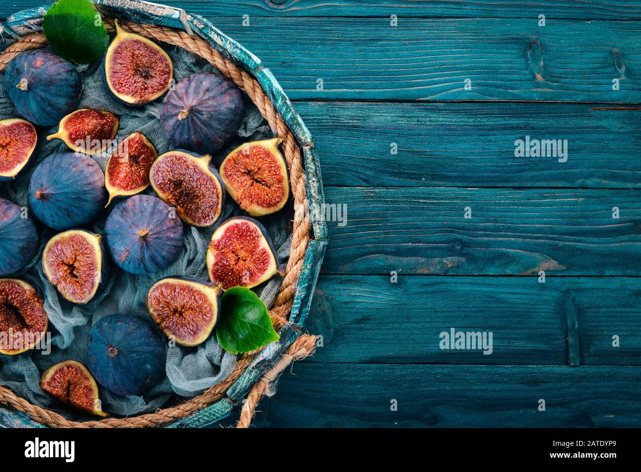 Fresh figs in a wooden box on a blue background. Free space for text ...