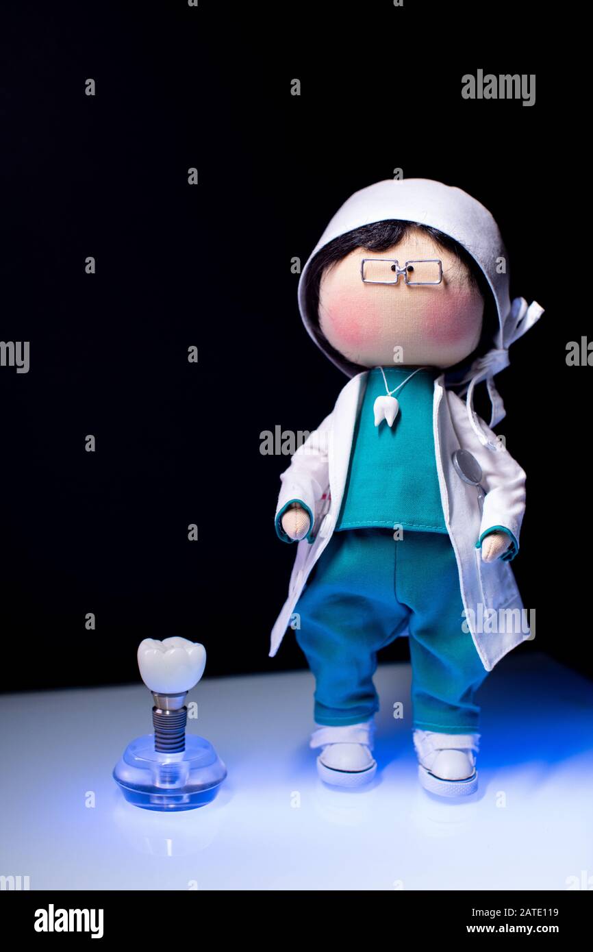 Full-length dentist doll. A dental implant model is placed next to the ...