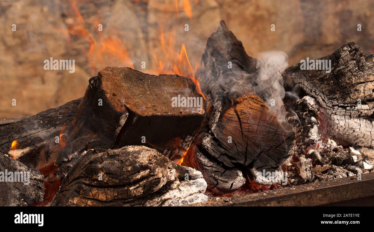 live fire cooking, coals and unburnt pieces of wood burning in a metal ...