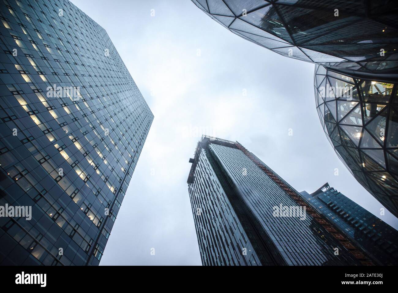 Looking up at skyscraper office towers with airplane flying overhead ...