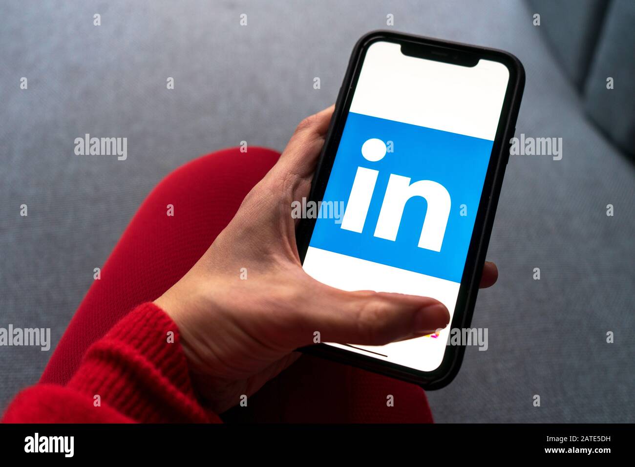 Young woman holding a smartphone with Linkedin app on screen. IPhone 11 ...