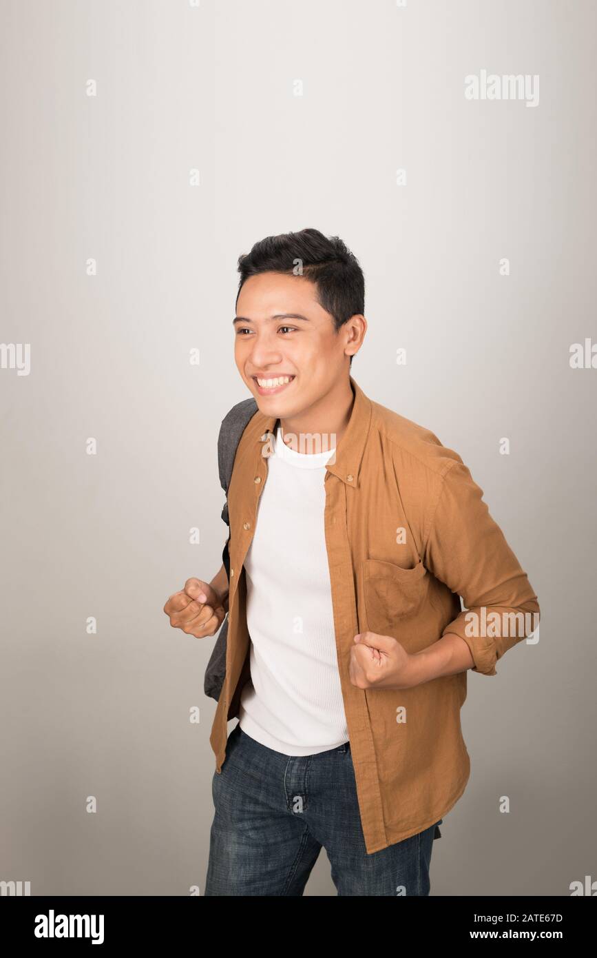 Young Asian student celebrating success isolated over white background ...