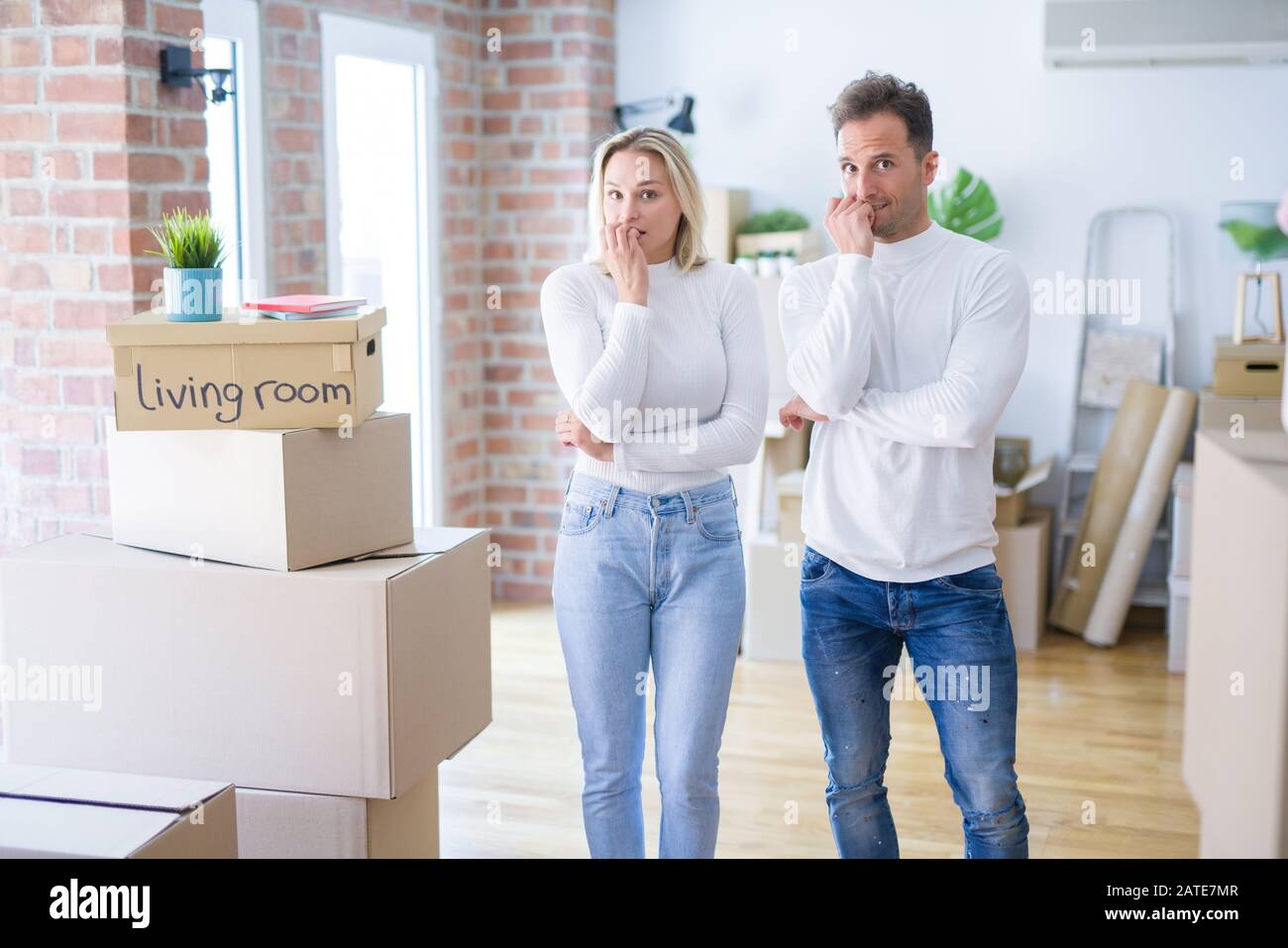 Young beautiful couple standing at new home around cardboard boxes ...