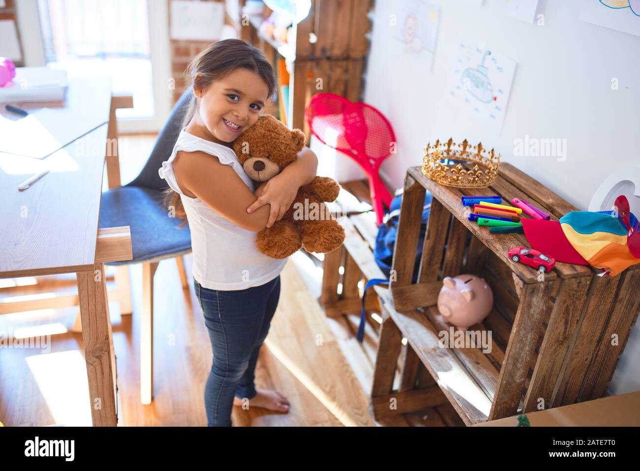 Adorable toddler smiling happy hugging teddy bear around lots of toys ...