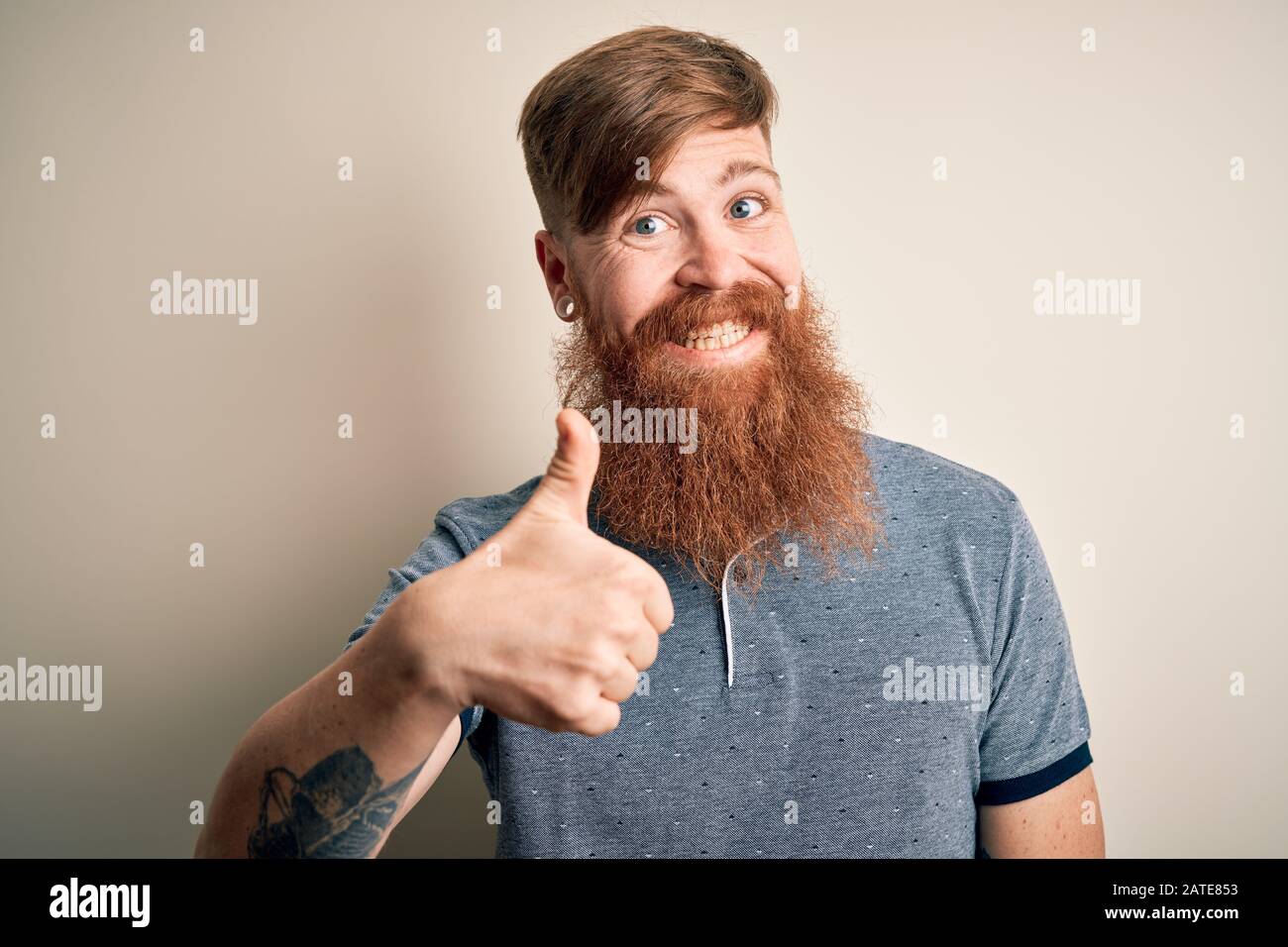 Handsome Irish redhead man with beard and arm tattoo standing over ...