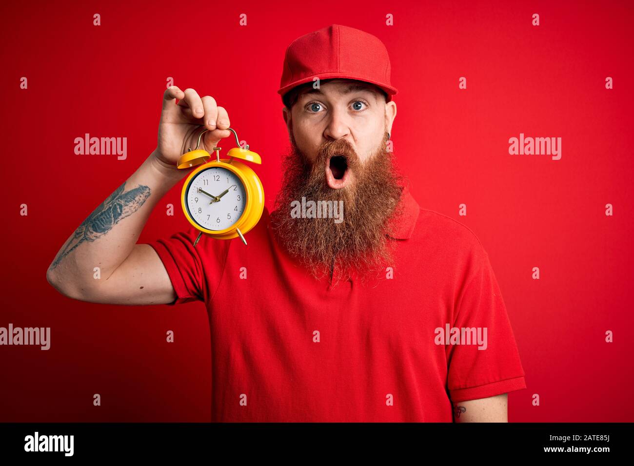 Redhead Irish delivery man with beard holding alarm clock for deadline ...