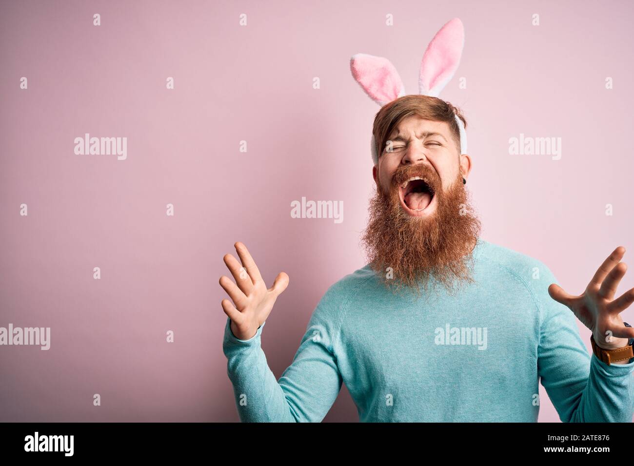 Hipster Irish man with beard wearing easter rabbit ears over isolated ...