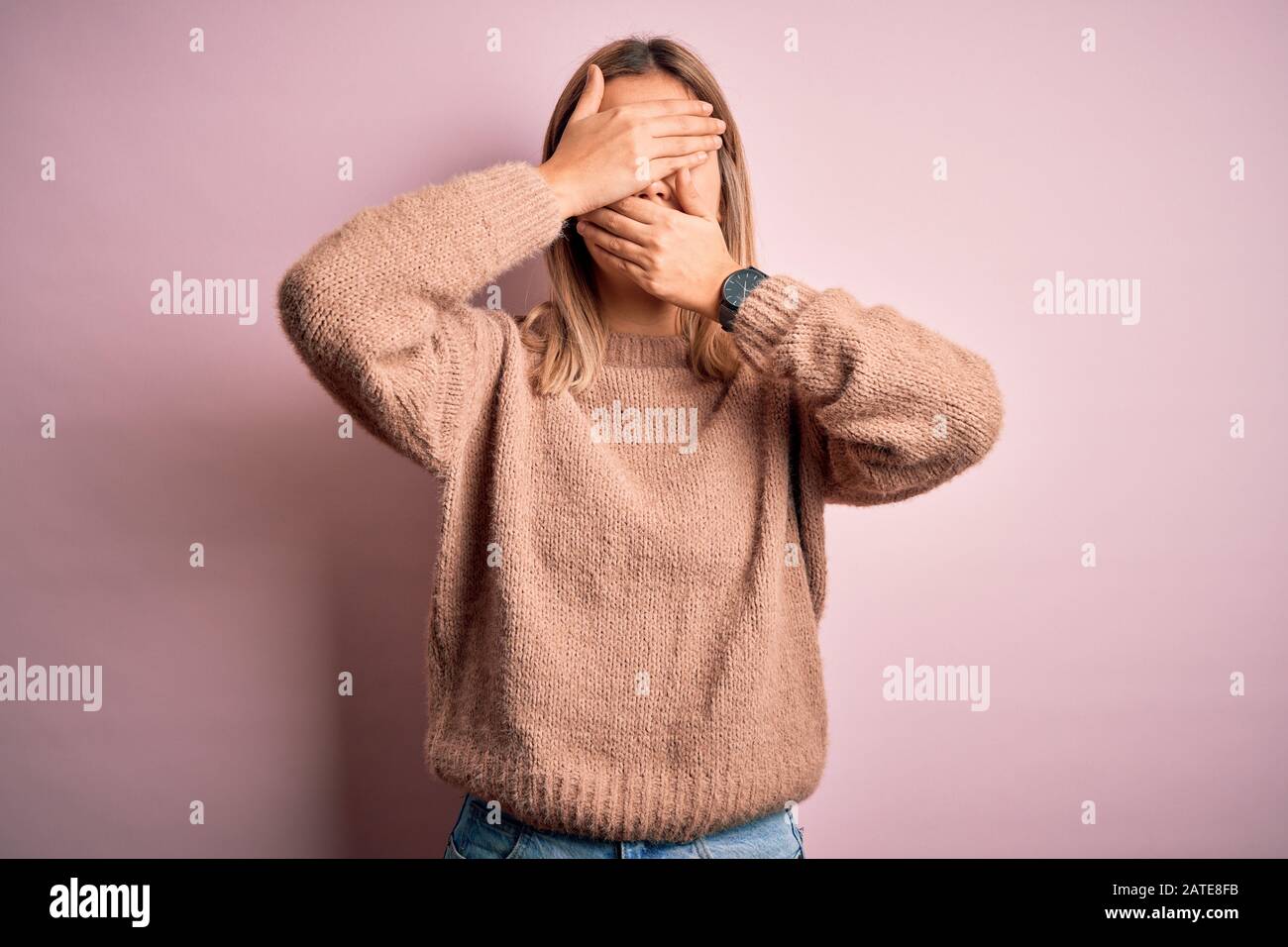 Young beautiful blonde woman wearing winter wool sweater over pink ...