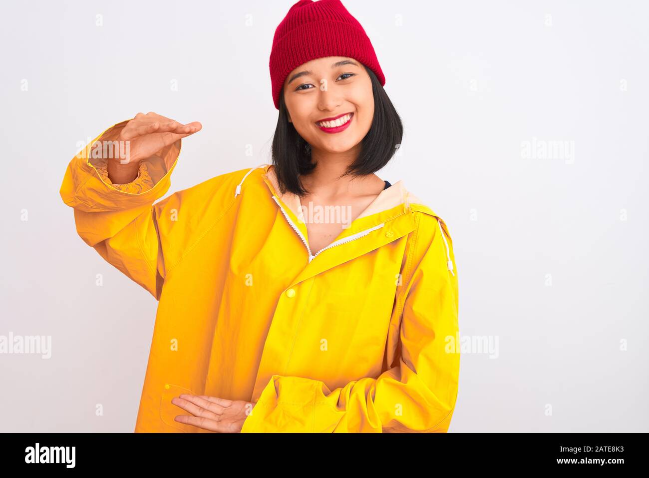 Young beautiful chinese woman wearing raincoat and wool cap over ...