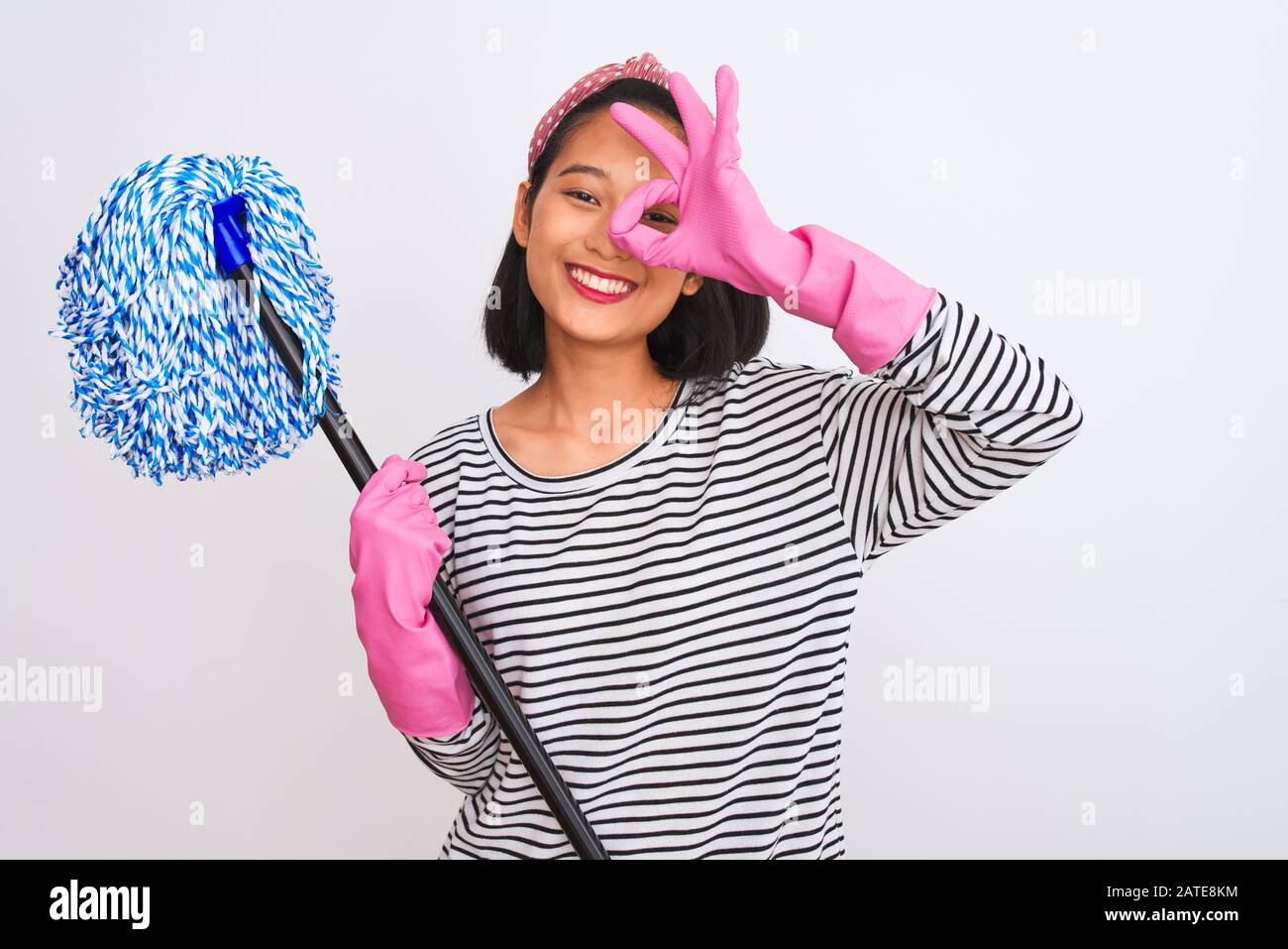 Young chinese cleaner woman wearing gloves holding mop over isolated ...