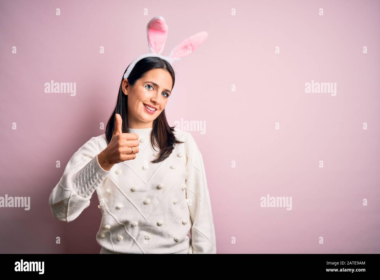 Young caucasian woman wearing cute easter rabbit ears over pink ...