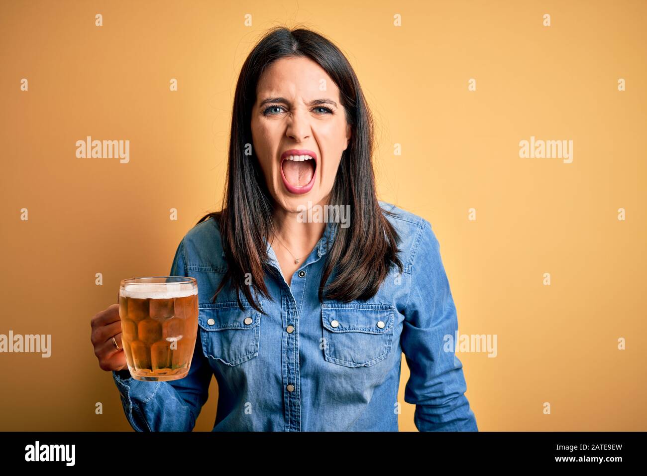 Young woman with blue eyes drinking jar of beer standing over isolated ...