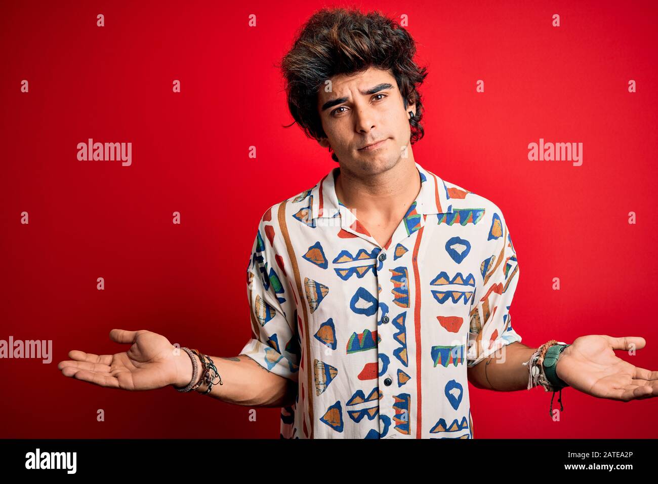 Young handsome man on vacation wearing summer shirt over isolated red ...