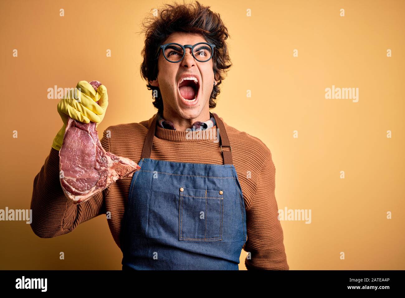 Young handsome butcher man holding meet steak standing over isolated ...