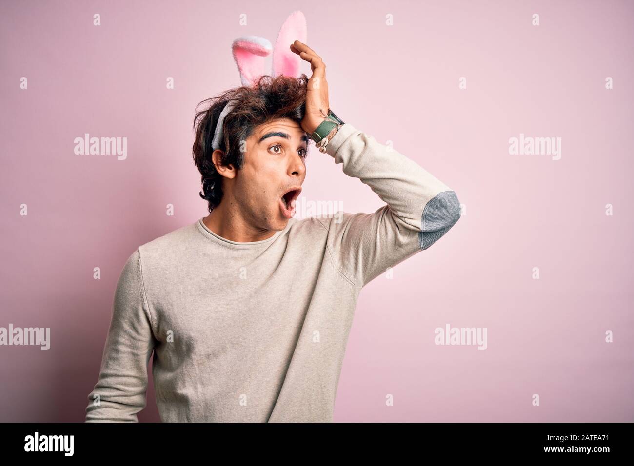Young handsome man holding easter rabbit ears standing over isolated ...