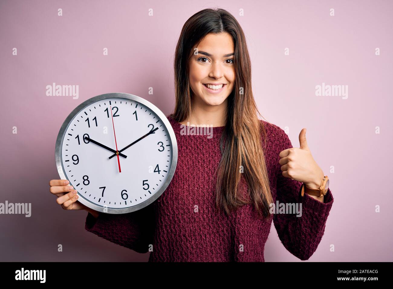 Young beautiful girl doing countdown holding big clock over isolated ...