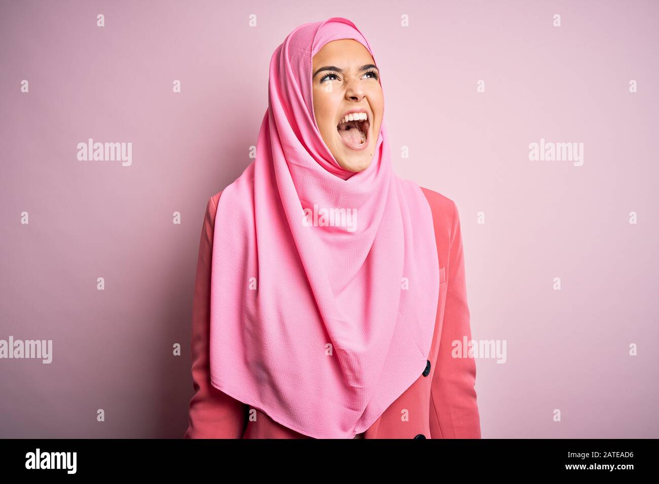 Young beautiful girl wearing muslim hijab standing over isolated pink ...