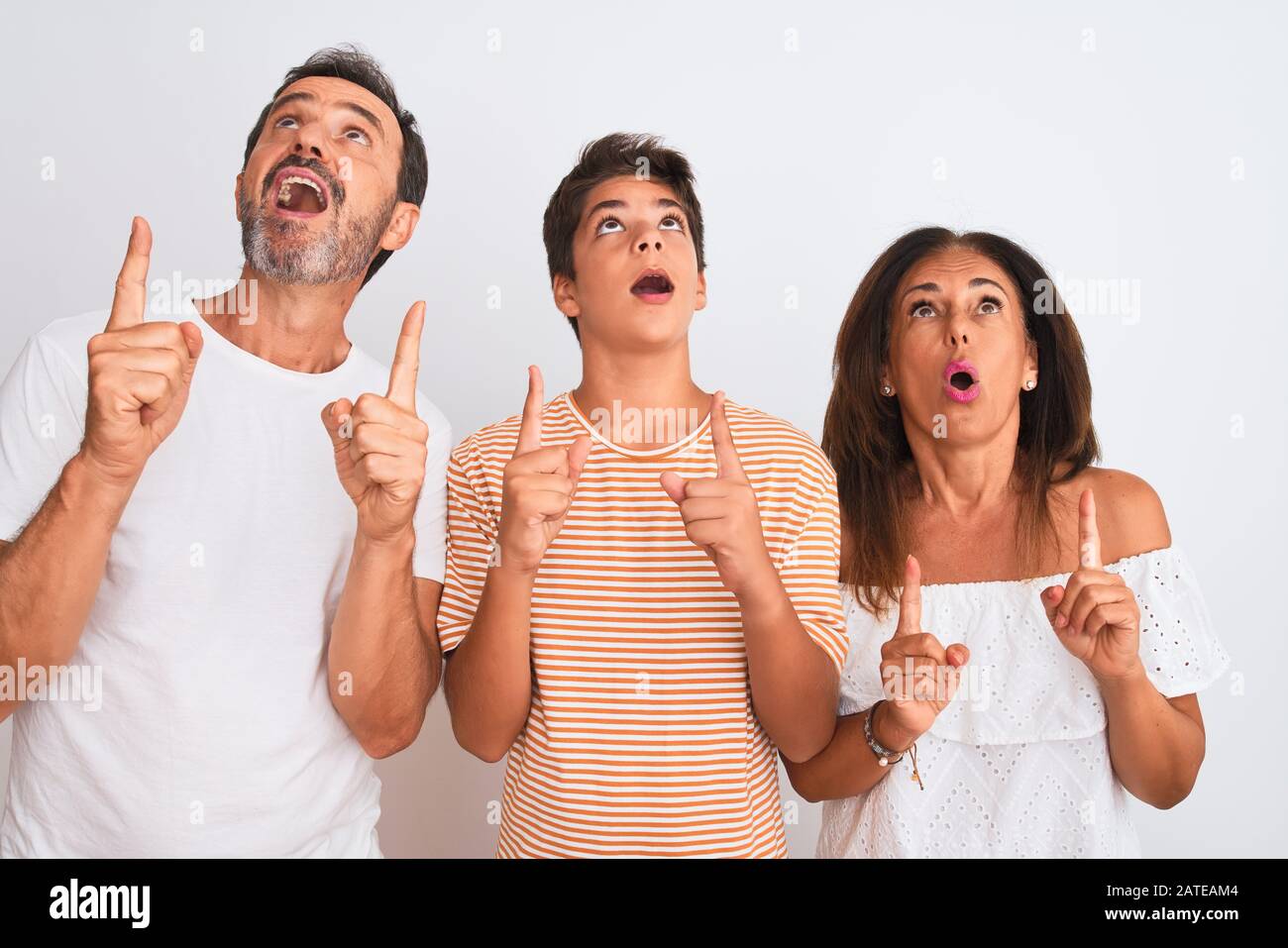Family of three, mother, father and son standing over white isolated ...