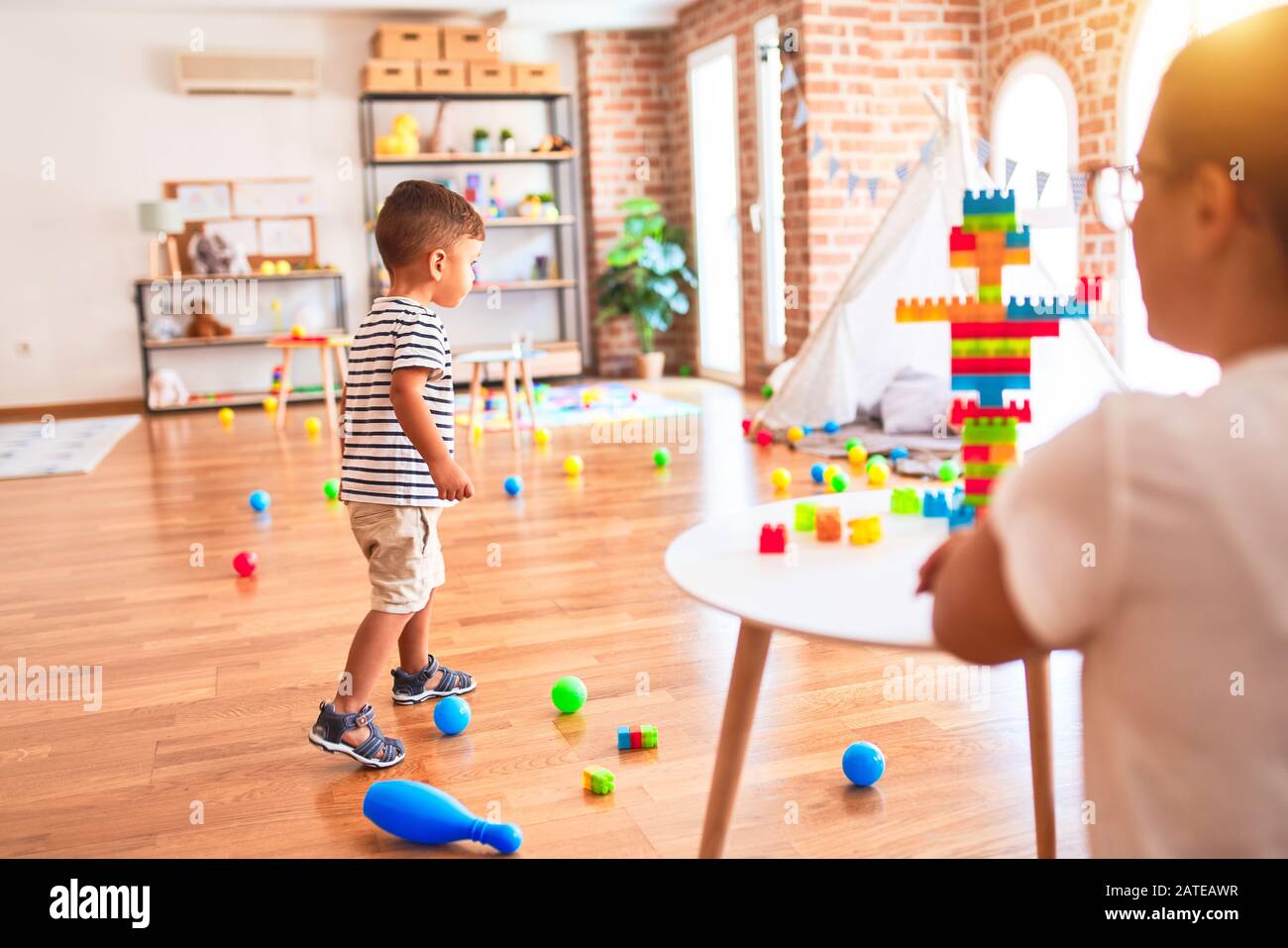 Beautiful teacher and toddler boy playing with construction blocks ...