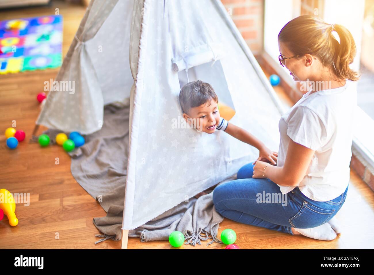 Beautiful teacher and toddler boy sitting on the floor playing inside ...