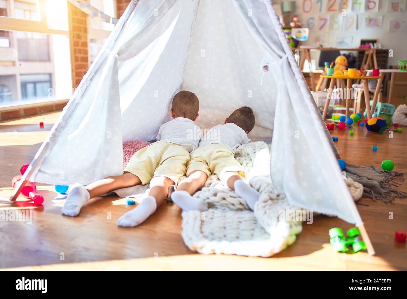 Adorable blonde twins playing inside tipi around lots of toys at ...