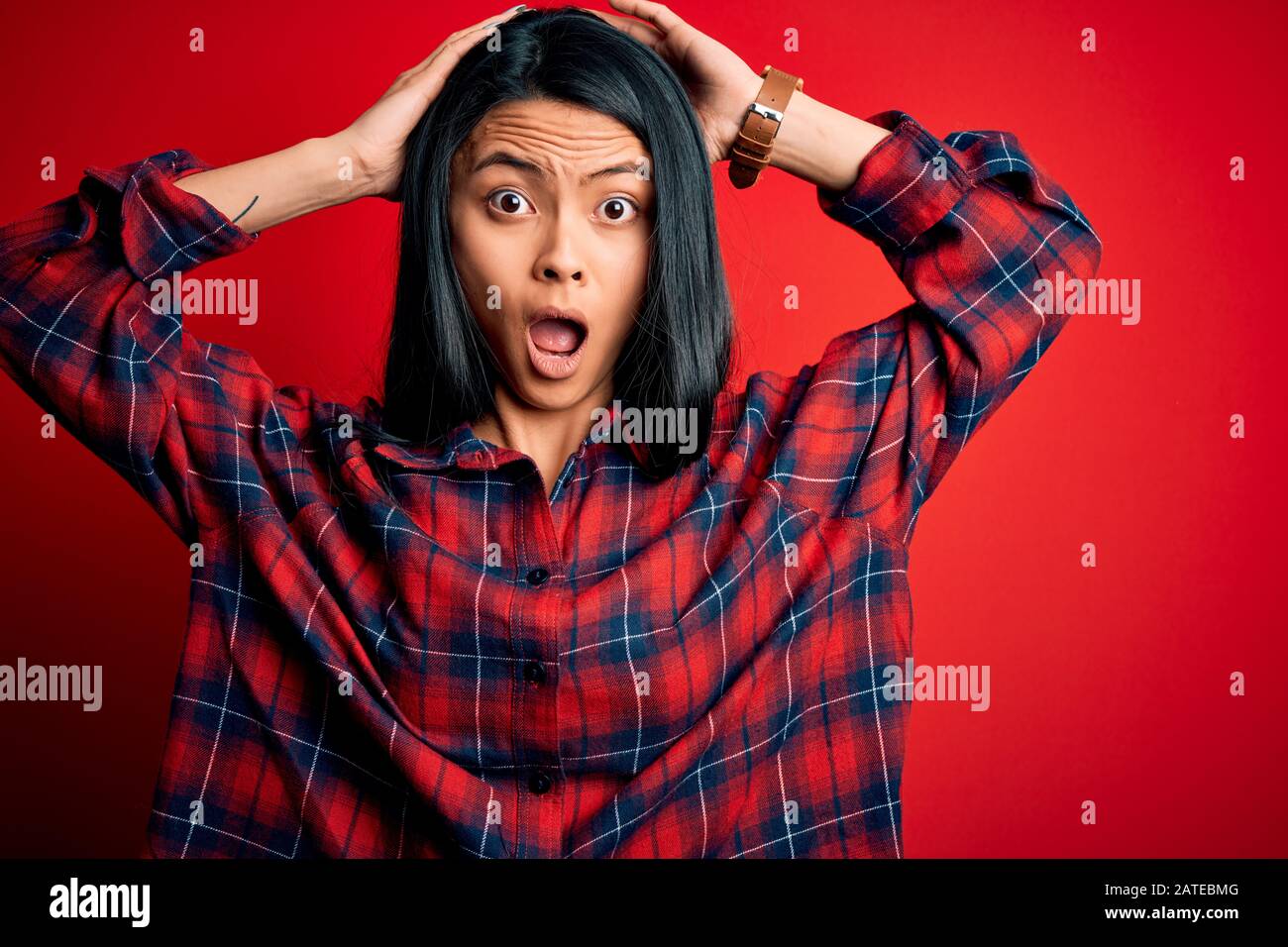 Young beautiful chinese woman wearing casual shirt over isolated red ...